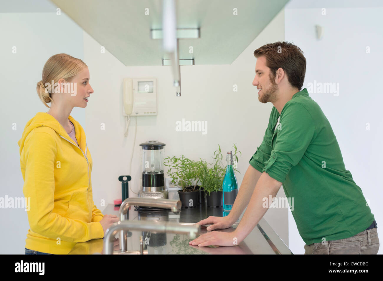 Couple talking across the kitchen counter Stock Photo - Alamy