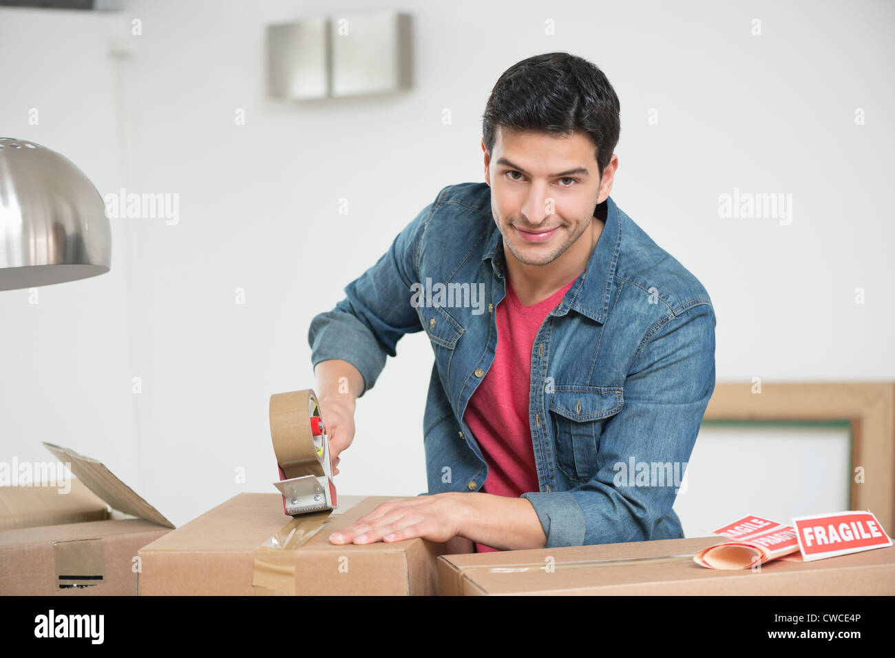 Man taping up a cardboard box Stock Photo - Alamy
