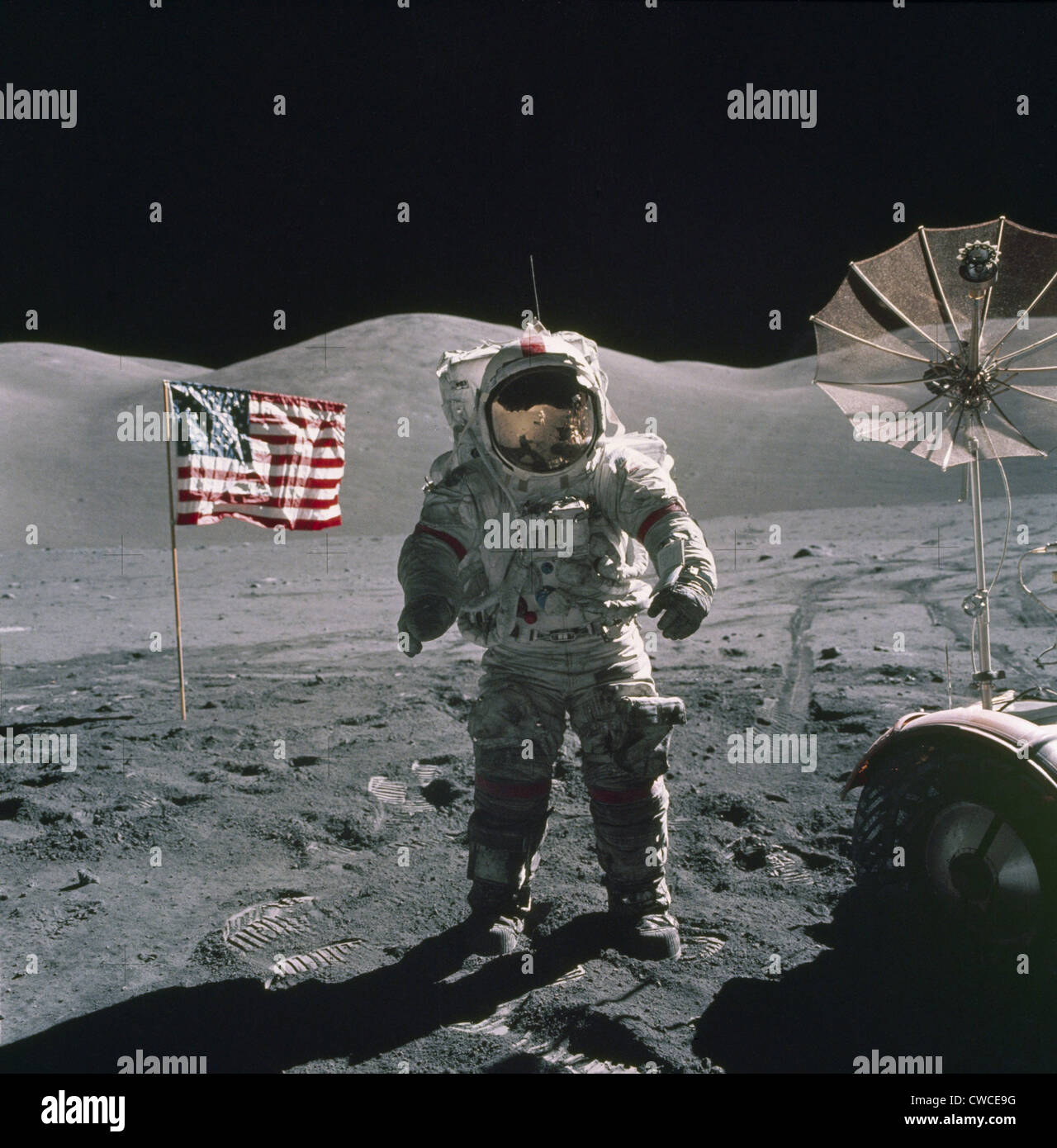 Apollo 17 Astronaut stands between a US flag and the Lunar Rover during ...
