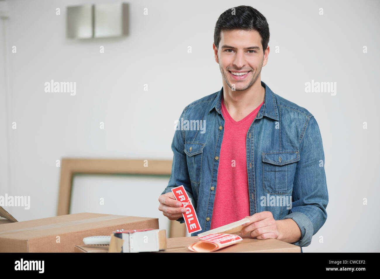 Man sticking 'Fragile' sticker on cardboard boxes Stock Photo - Alamy