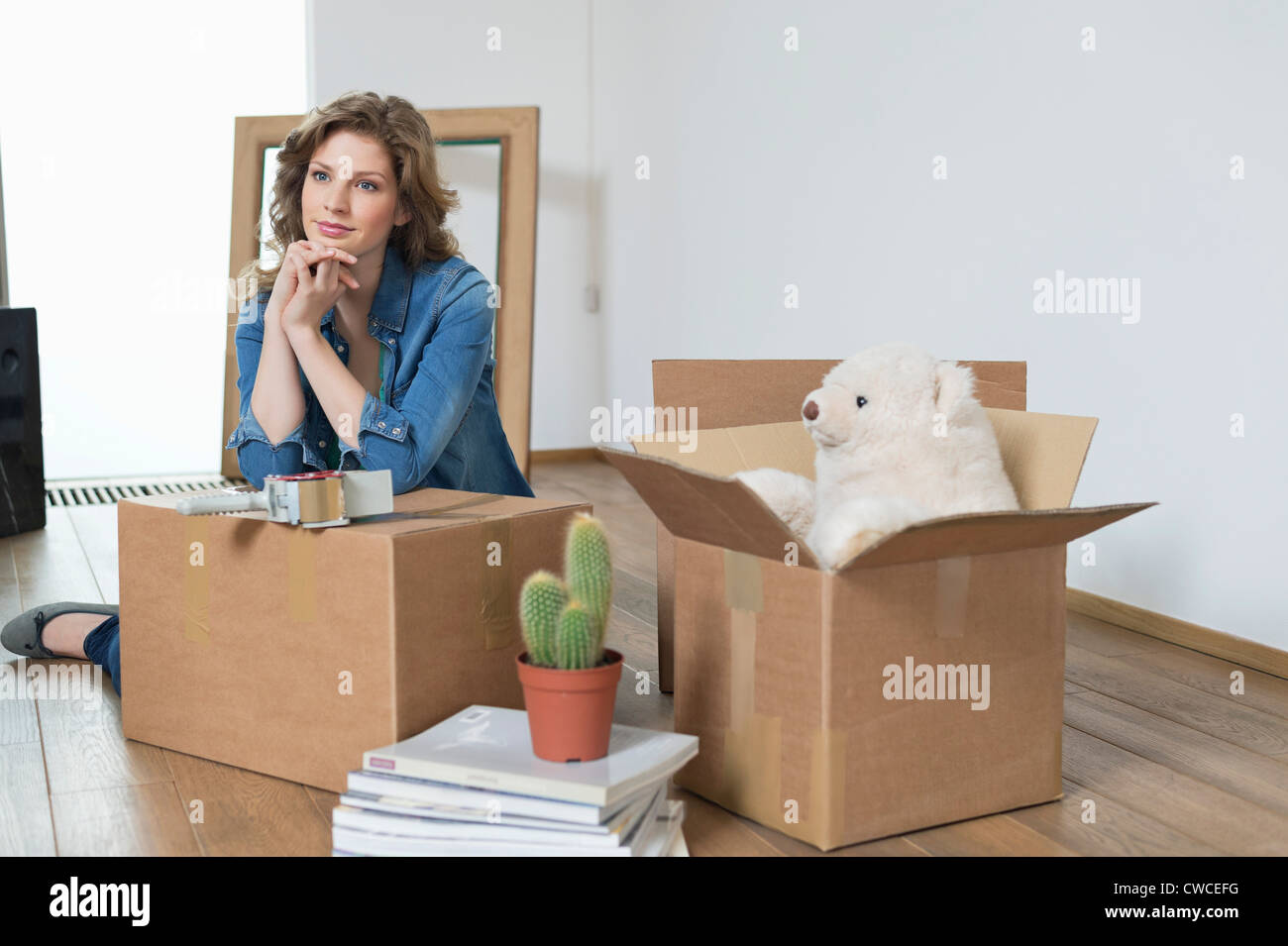 Woman leaning on cardboard box and thinking Stock Photo - Alamy