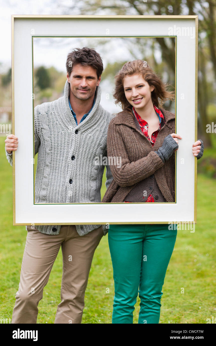 Portrait of a couple holding a frame Stock Photo - Alamy