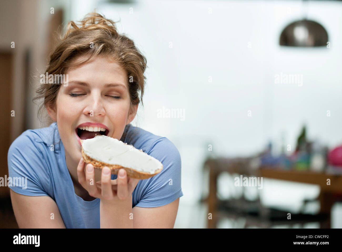 Woman eating toast with cream spread on it Stock Photo - Alamy