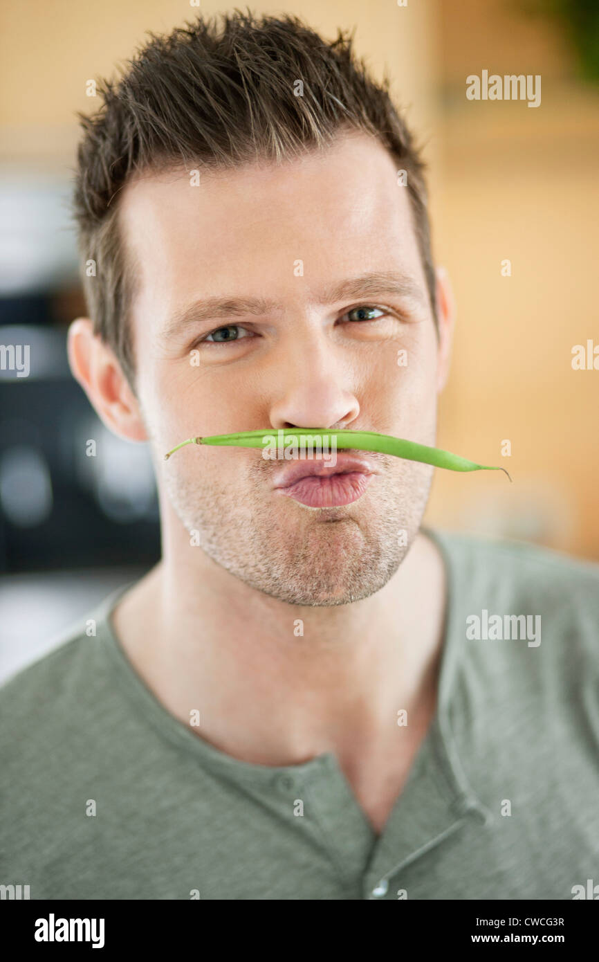 Man making artificial mustache with green bean Stock Photo - Alamy