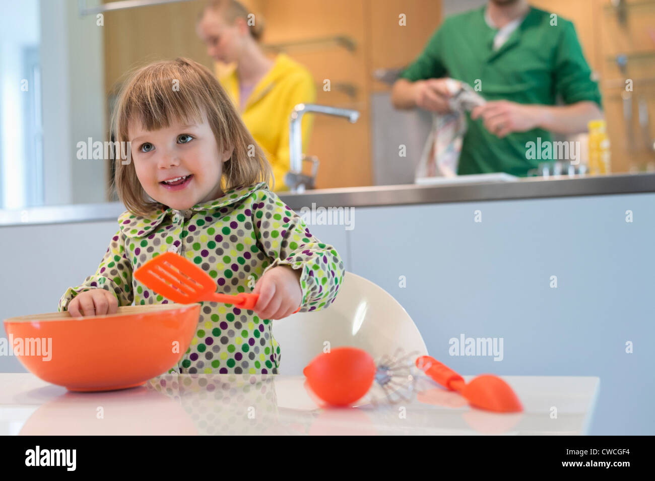 Cute little girl with slotted spoon and mixing bowl in the kitchen ...