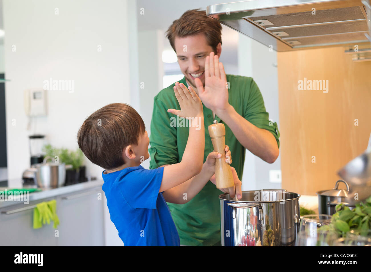 Man and son giving high five to each other in the kitchen Stock Photo ...