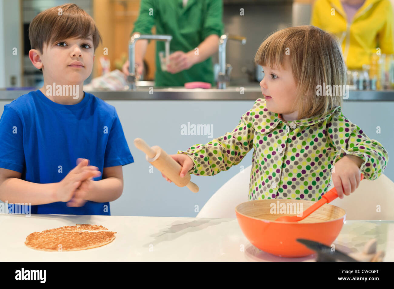 Children cooking in the kitchen with their parents in the background ...