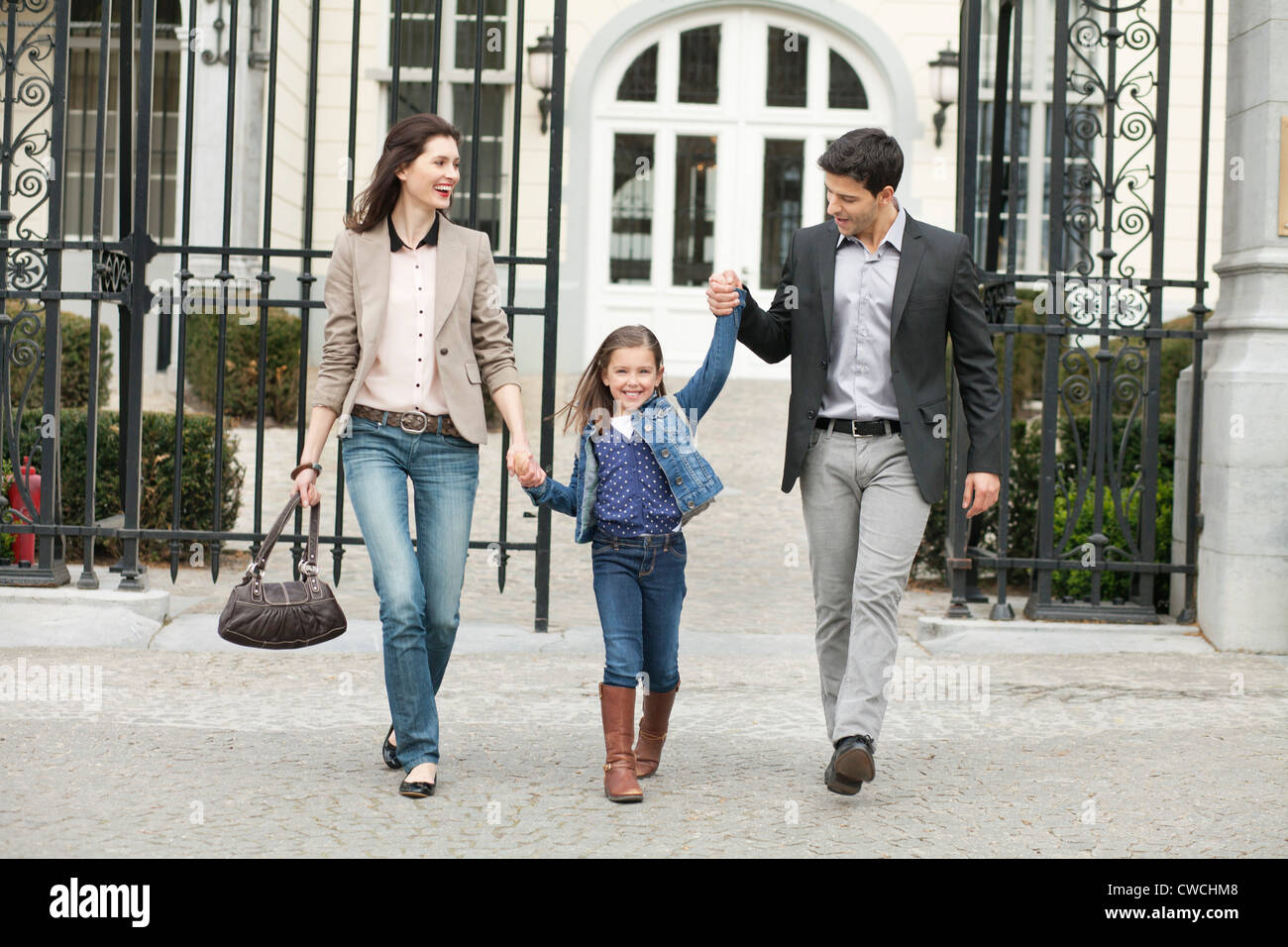 Portrait of a girl walking with her parents Stock Photo - Alamy