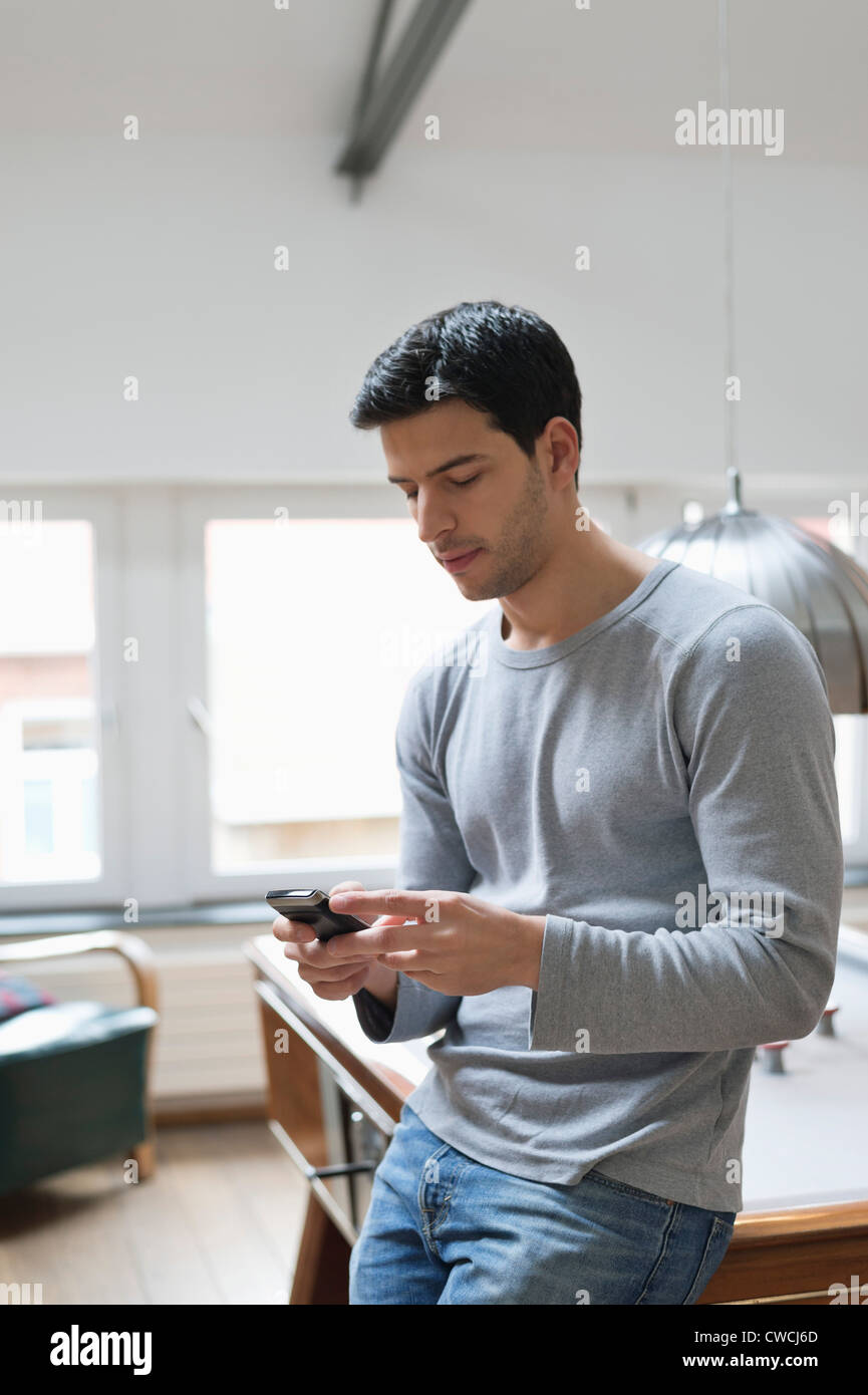 Man leaning against a pool table using a mobile phone Stock Photo - Alamy