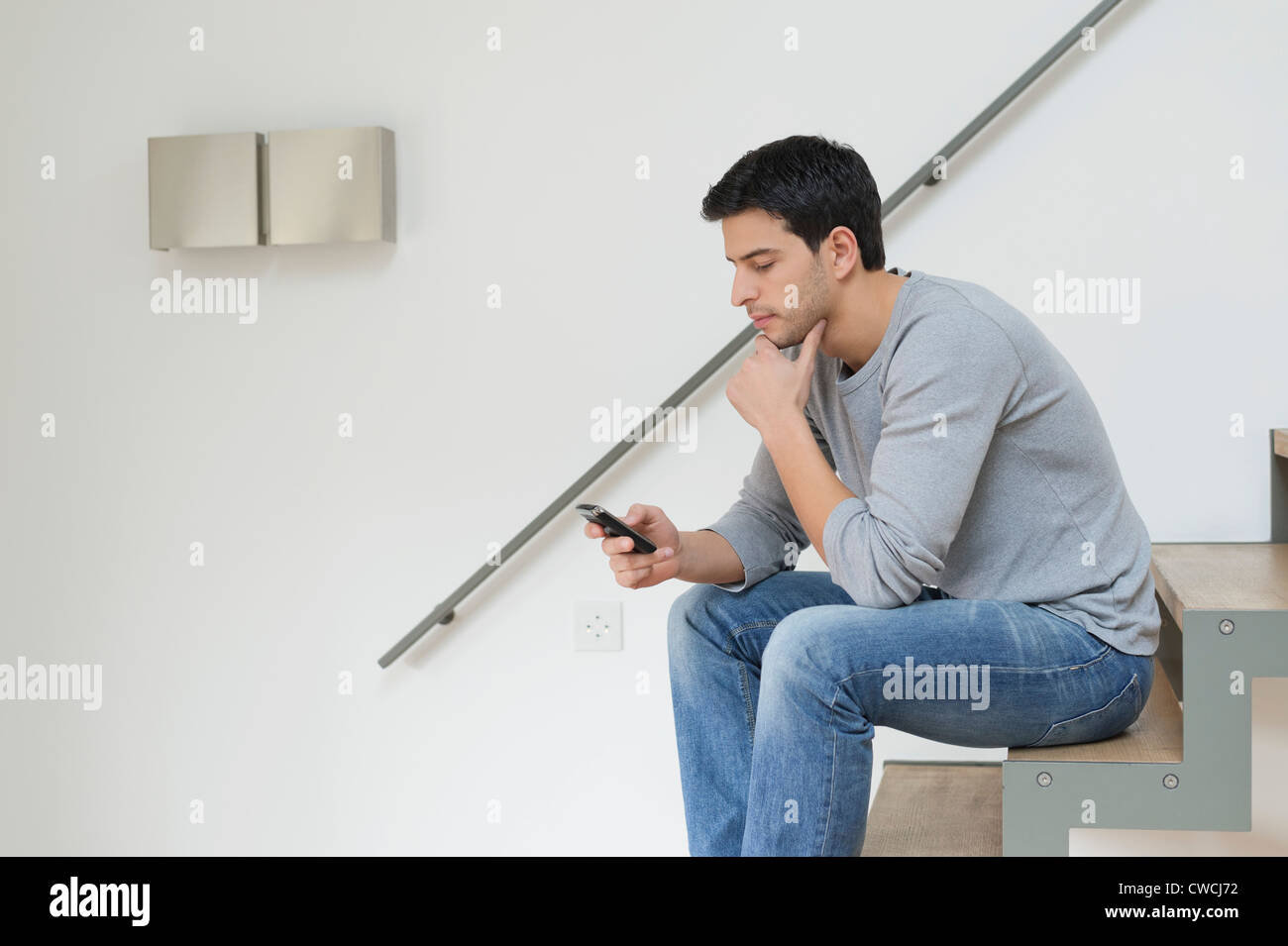 Man sitting on stairs using a mobile phone Stock Photo - Alamy