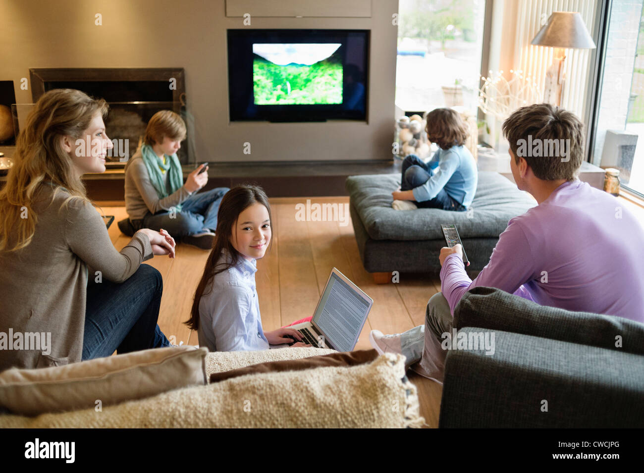 Family using electronic gadgets in a living room Stock Photo - Alamy