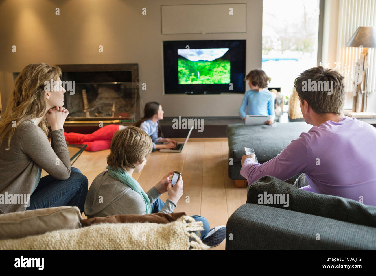 Family using electronic gadgets in a living room Stock Photo - Alamy