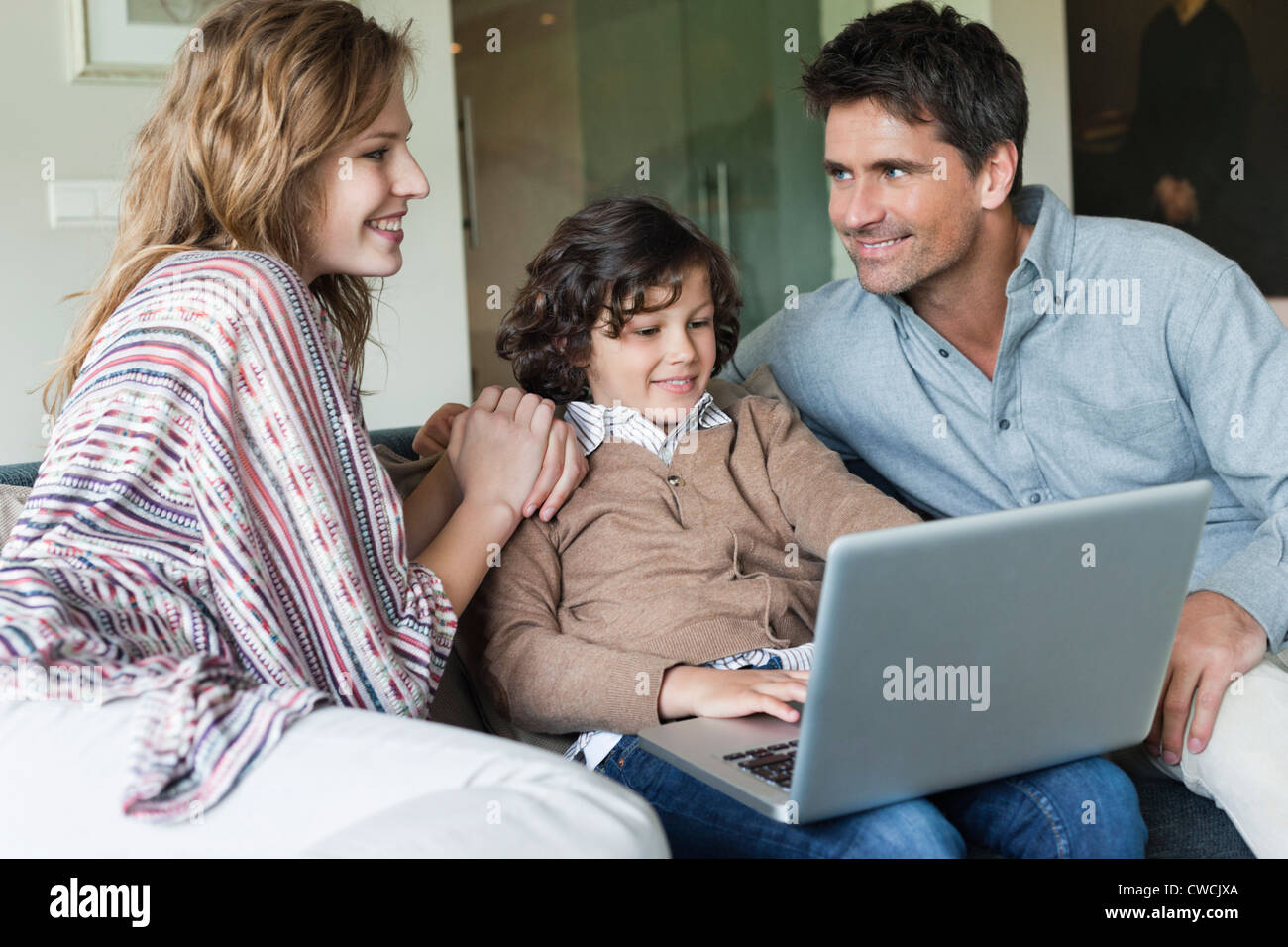 Boy using a laptop with his parents at home Stock Photo - Alamy