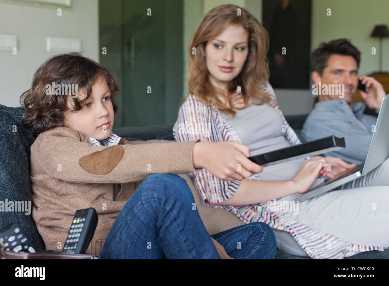 Family using electronic gadgets in a living room Stock Photo - Alamy