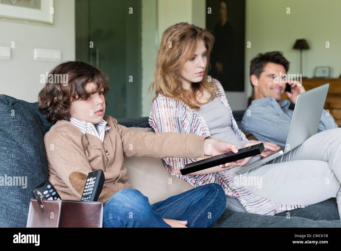 Family using electronic gadgets in a living room Stock Photo - Alamy