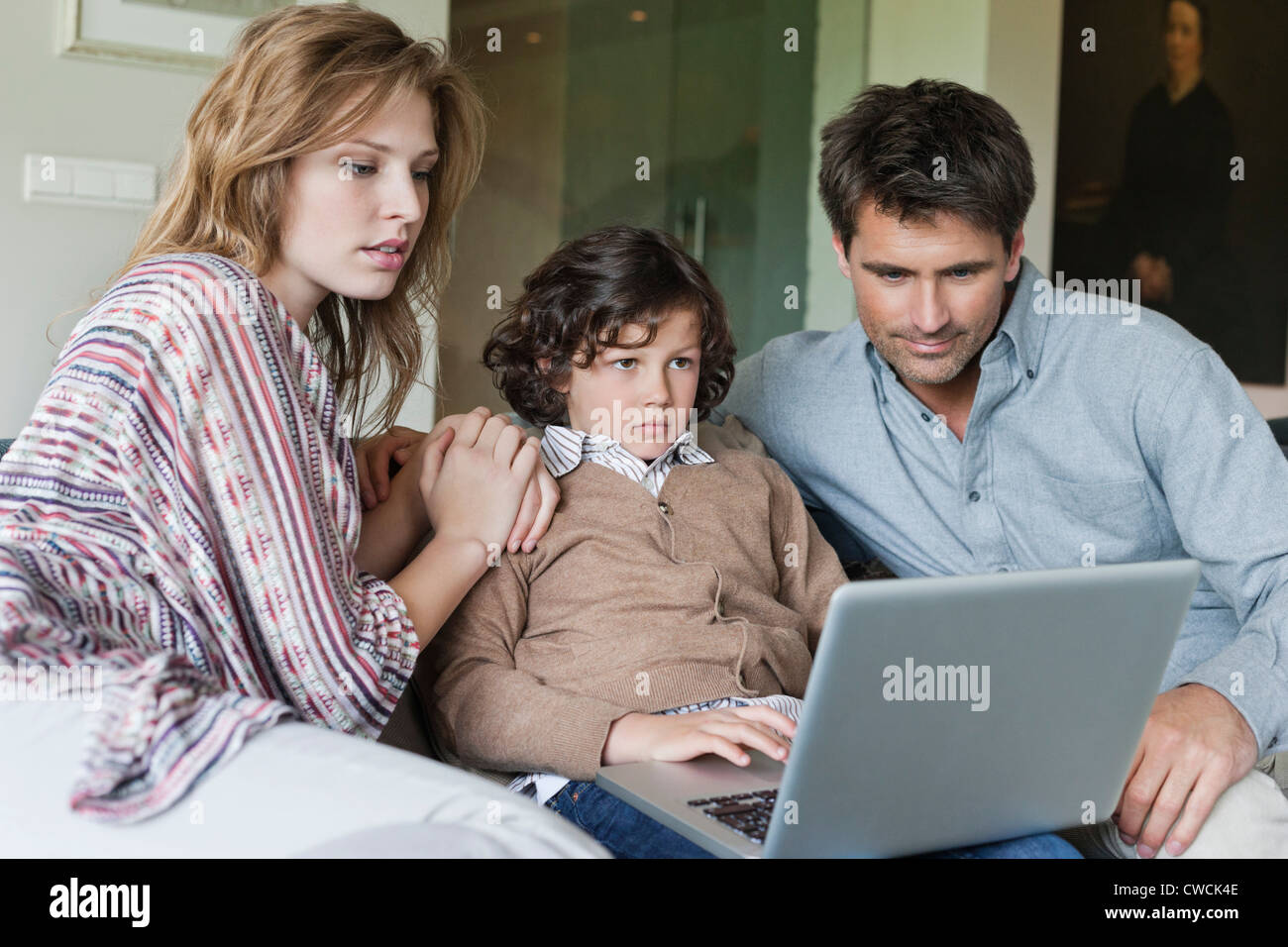 Boy using a laptop with his parents at home Stock Photo - Alamy