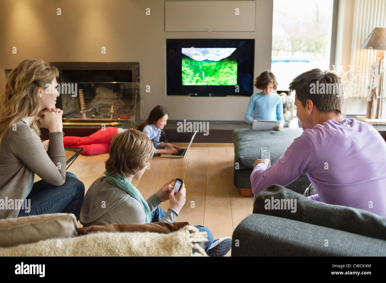 Family using electronic gadgets in a living room Stock Photo - Alamy