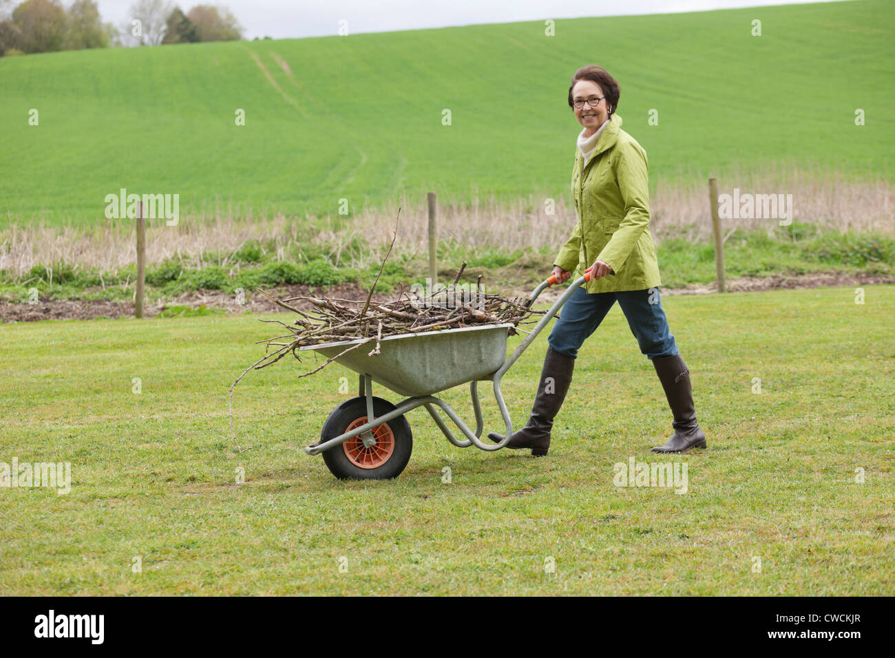 Woman pushing a wheelbarrow full of branches Stock Photo - Alamy