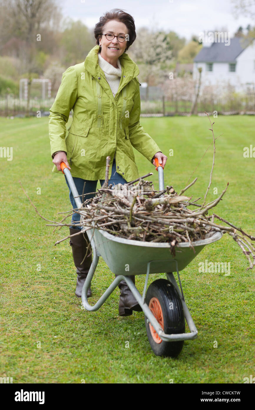 Woman pushing a wheelbarrow full of branches Stock Photo - Alamy