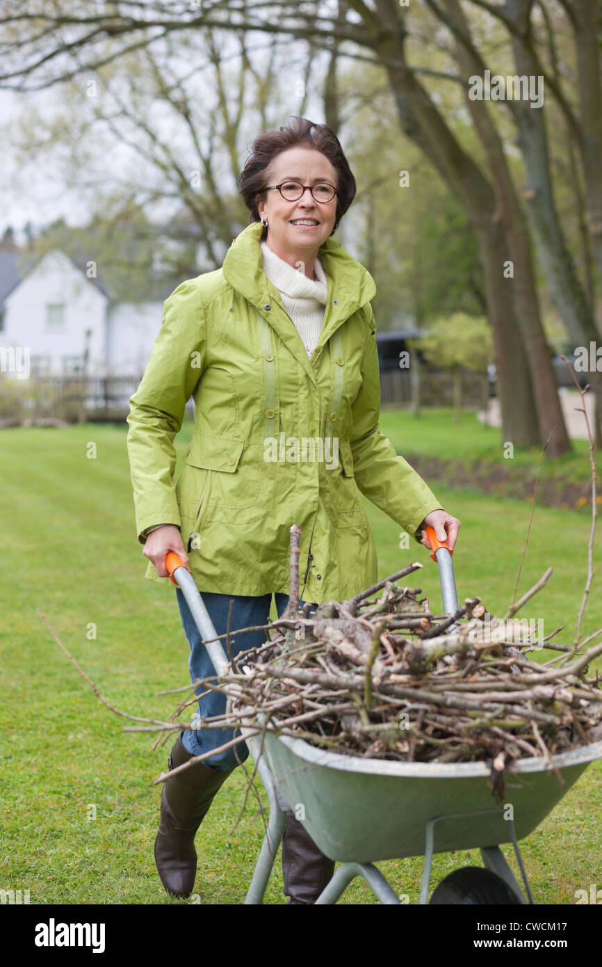 Woman pushing a wheelbarrow full of branches Stock Photo - Alamy