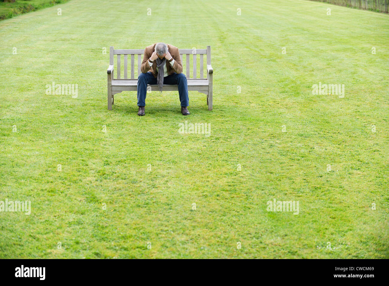 Depressed man sitting on a bench in a park Stock Photo - Alamy