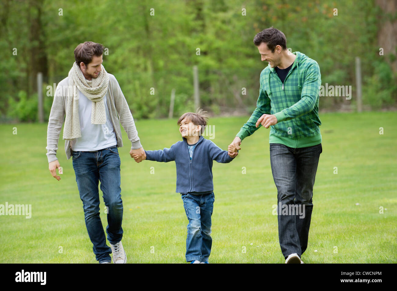 Boy walking with two men in a park Stock Photo - Alamy