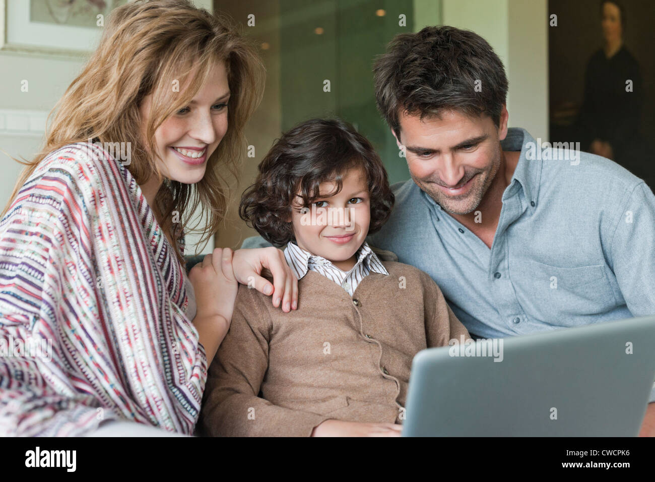 Boy using a laptop with his parents at home Stock Photo - Alamy