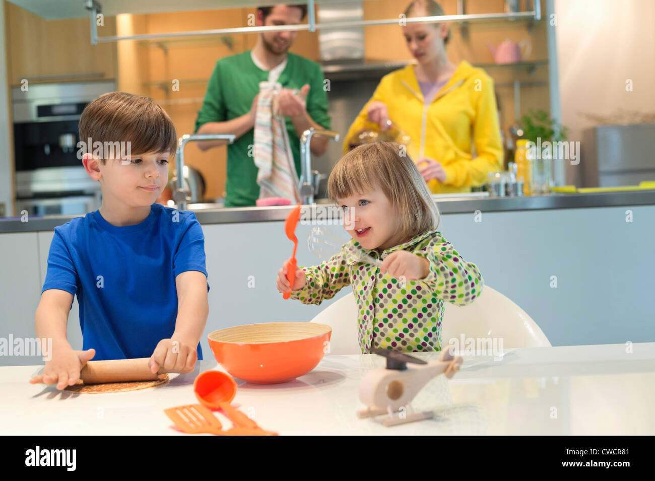 Children cooking in the kitchen with their parents in the background ...