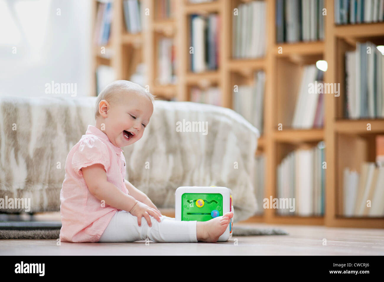 Baby girl playing with a musical block toy Stock Photo - Alamy