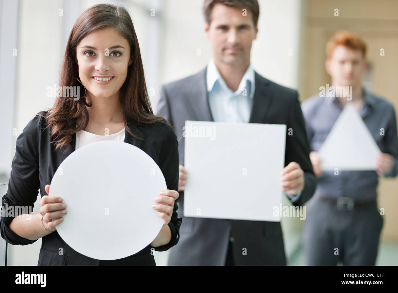 Business executives holding geometrical shaped placards in an office ...