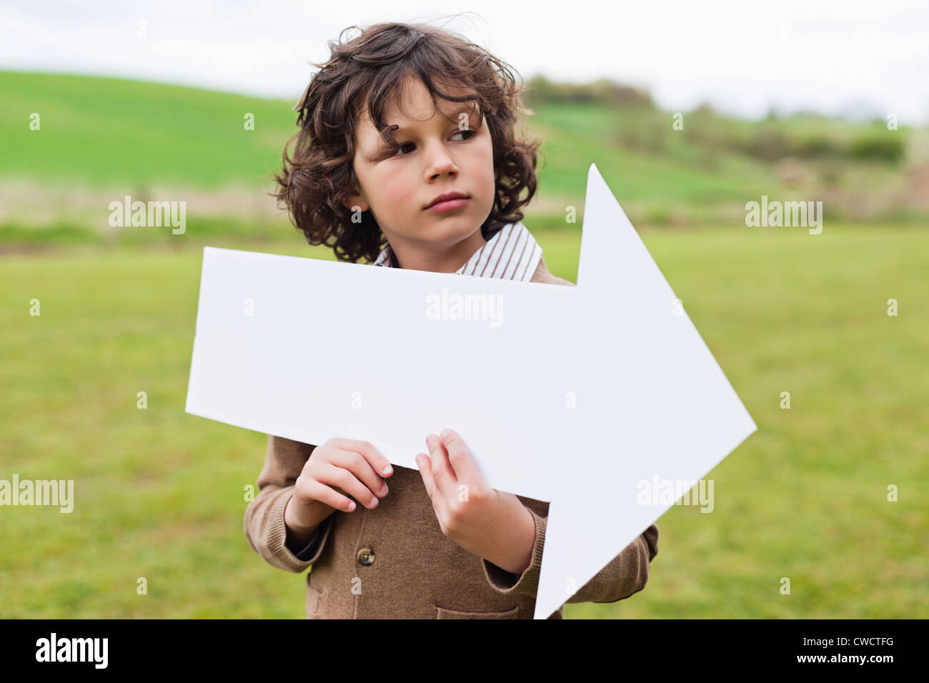 Boy holding an arrow sign in a field Stock Photo - Alamy