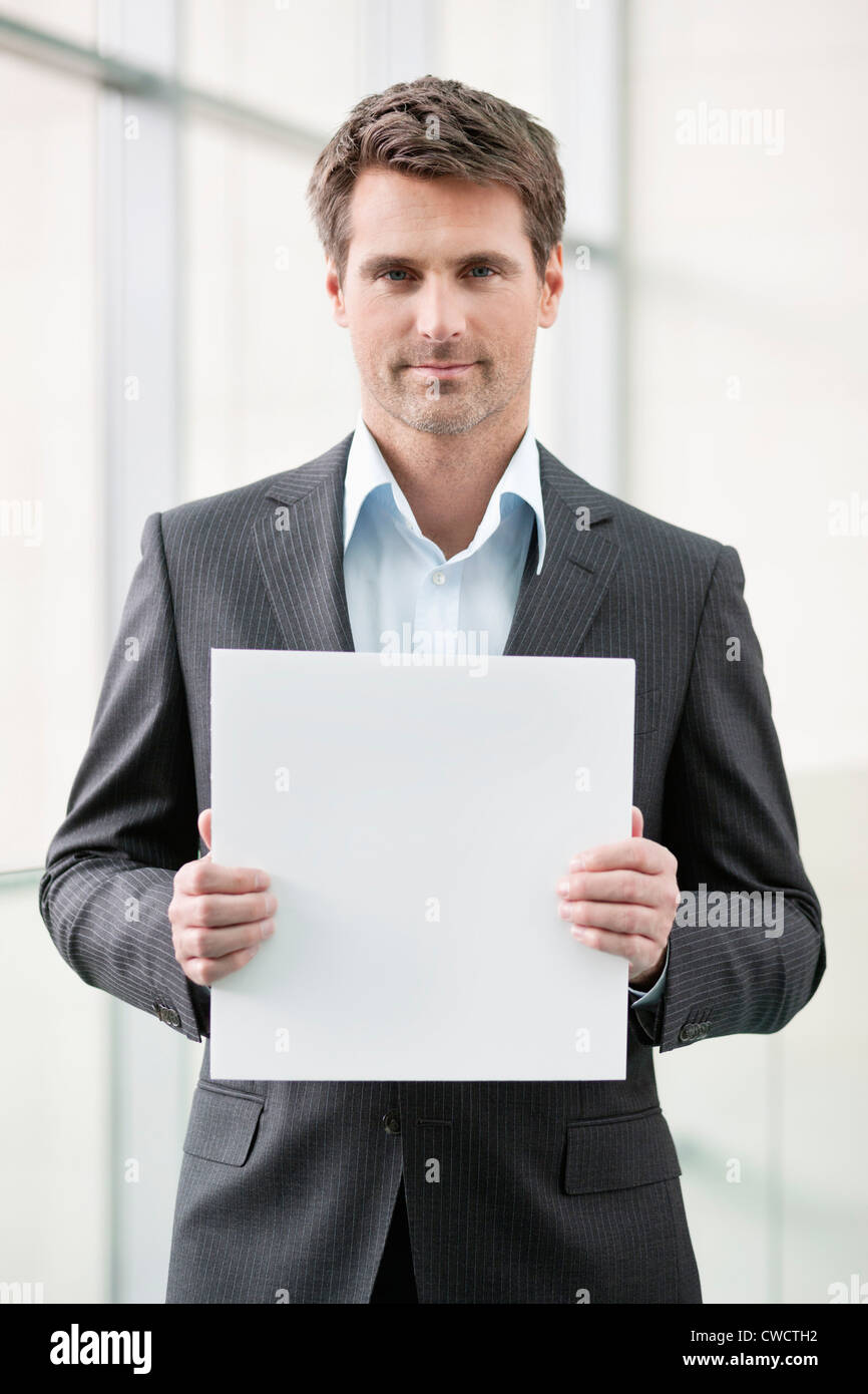Businessman holding a blank placard in an office Stock Photo - Alamy