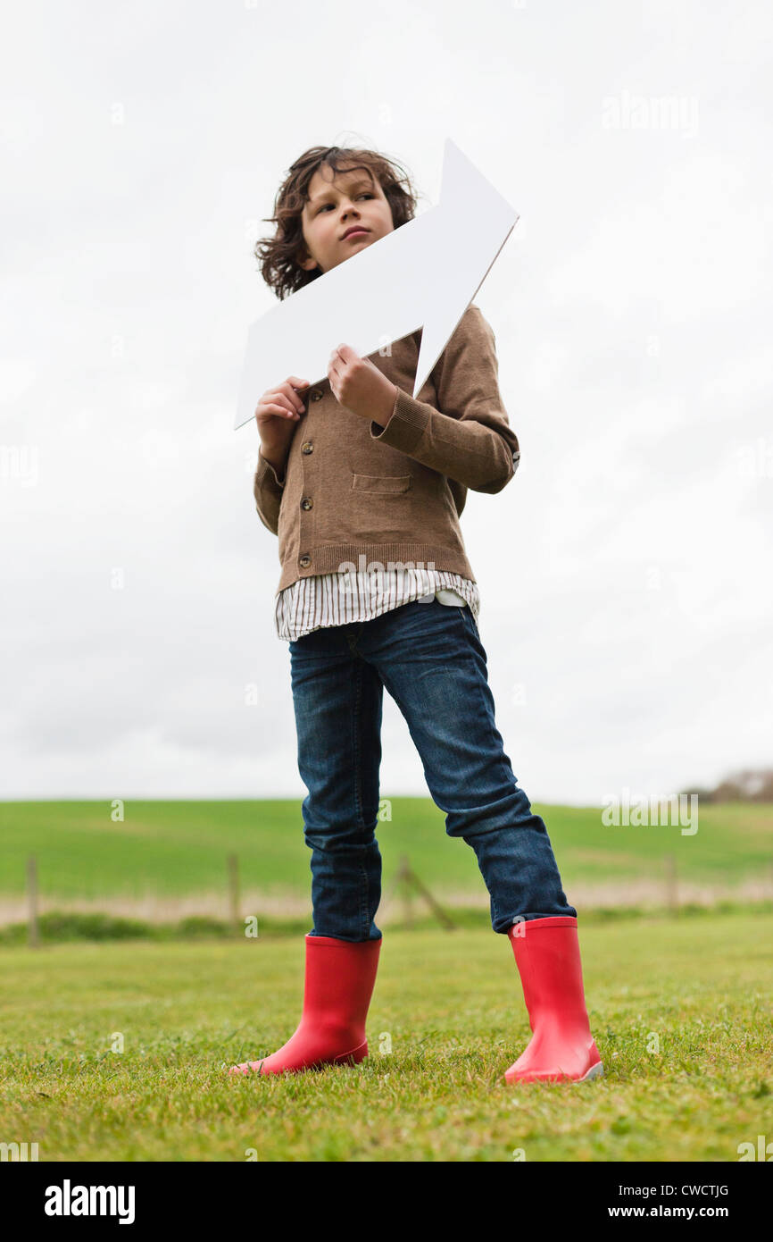 Boy holding an arrow sign in a field Stock Photo - Alamy
