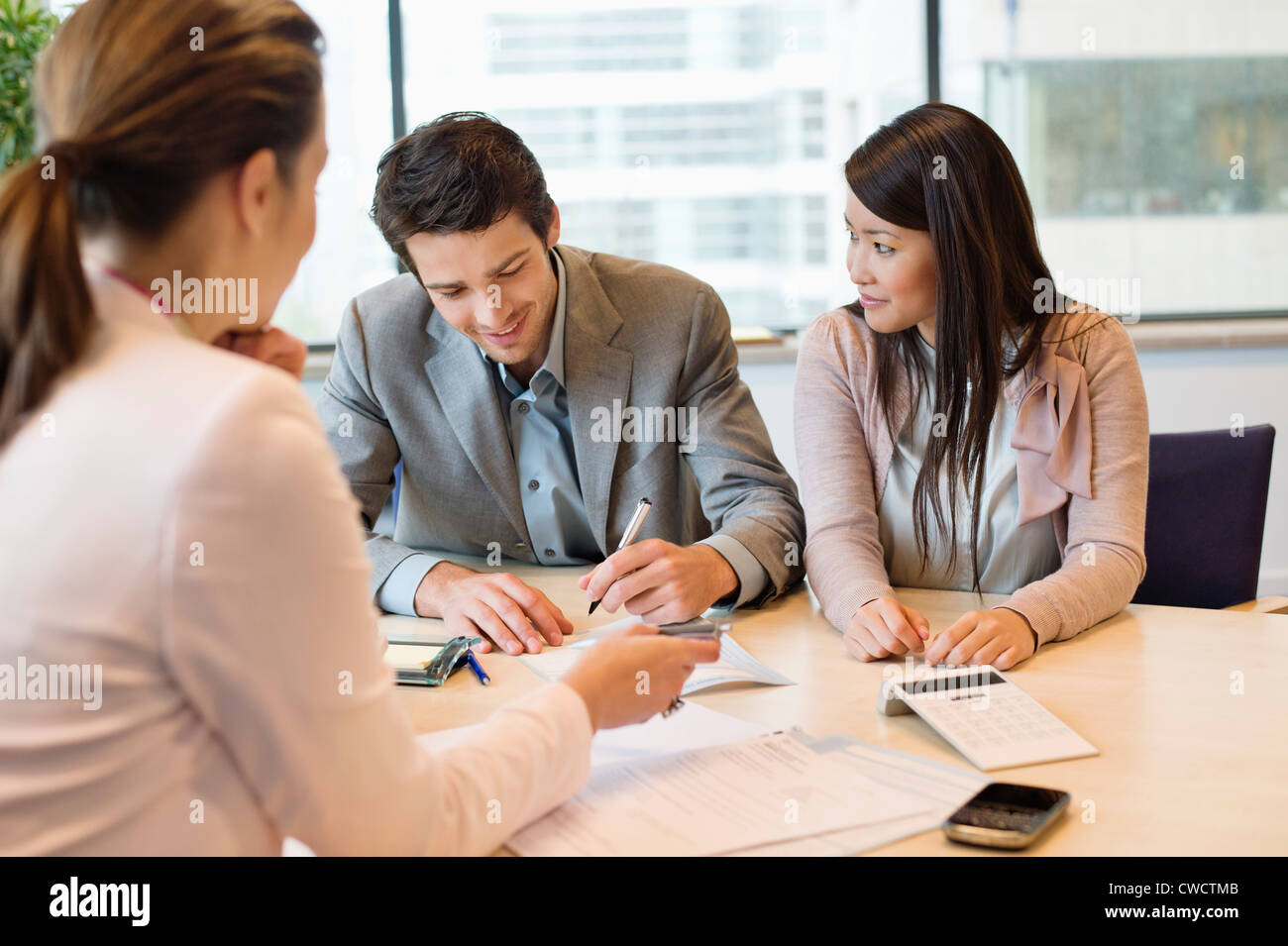 Couple signing documents with business executive Stock Photo - Alamy