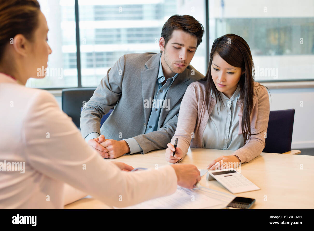 Couple signing documents with business executive Stock Photo - Alamy