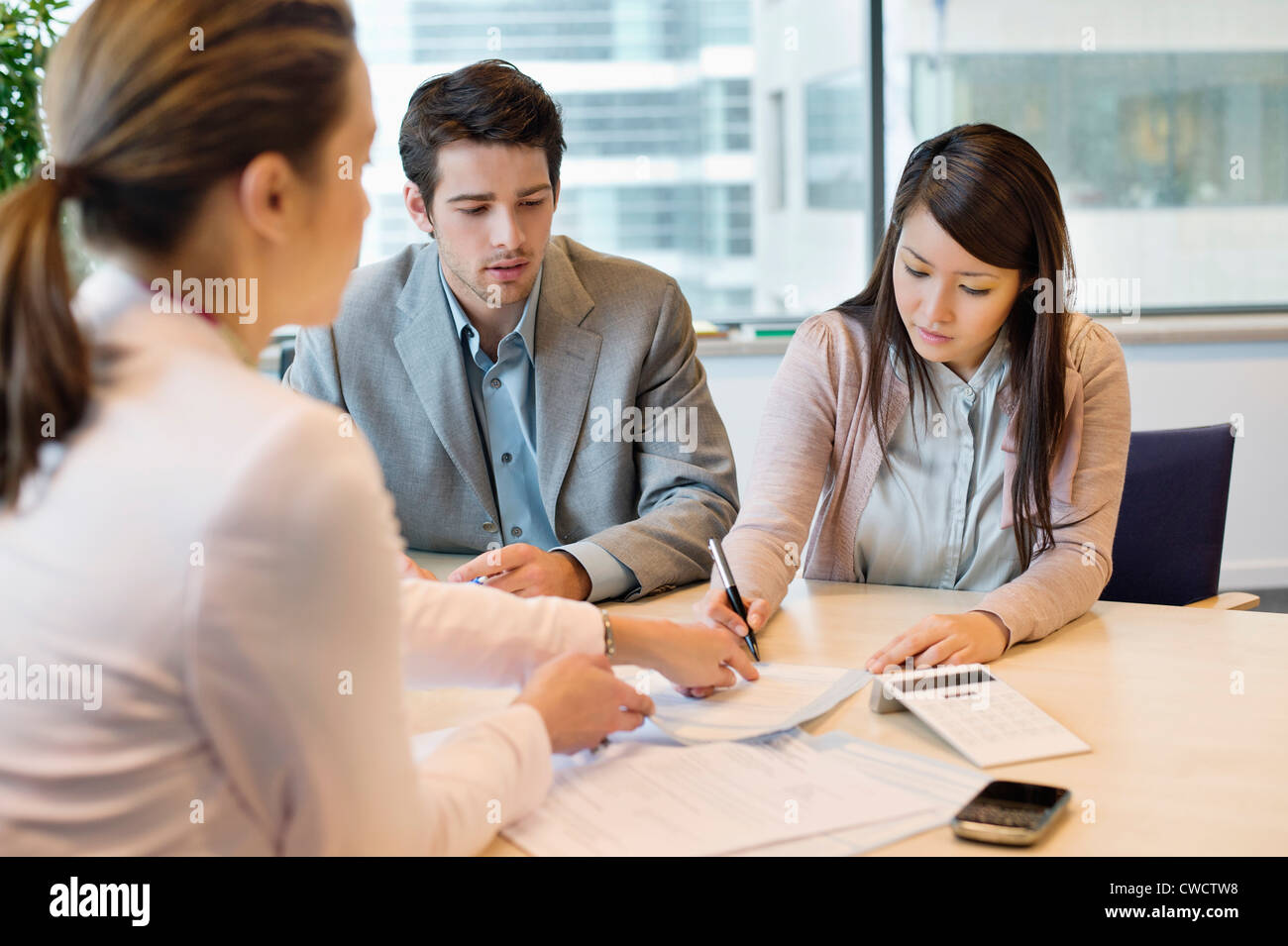 Couple signing documents with business executive Stock Photo - Alamy
