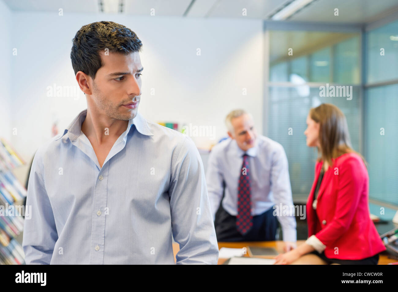 Male executive listening to his colleagues conversation in an office ...