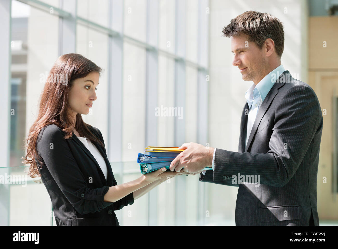 Businessmen giving files to his female colleague in an office Stock ...
