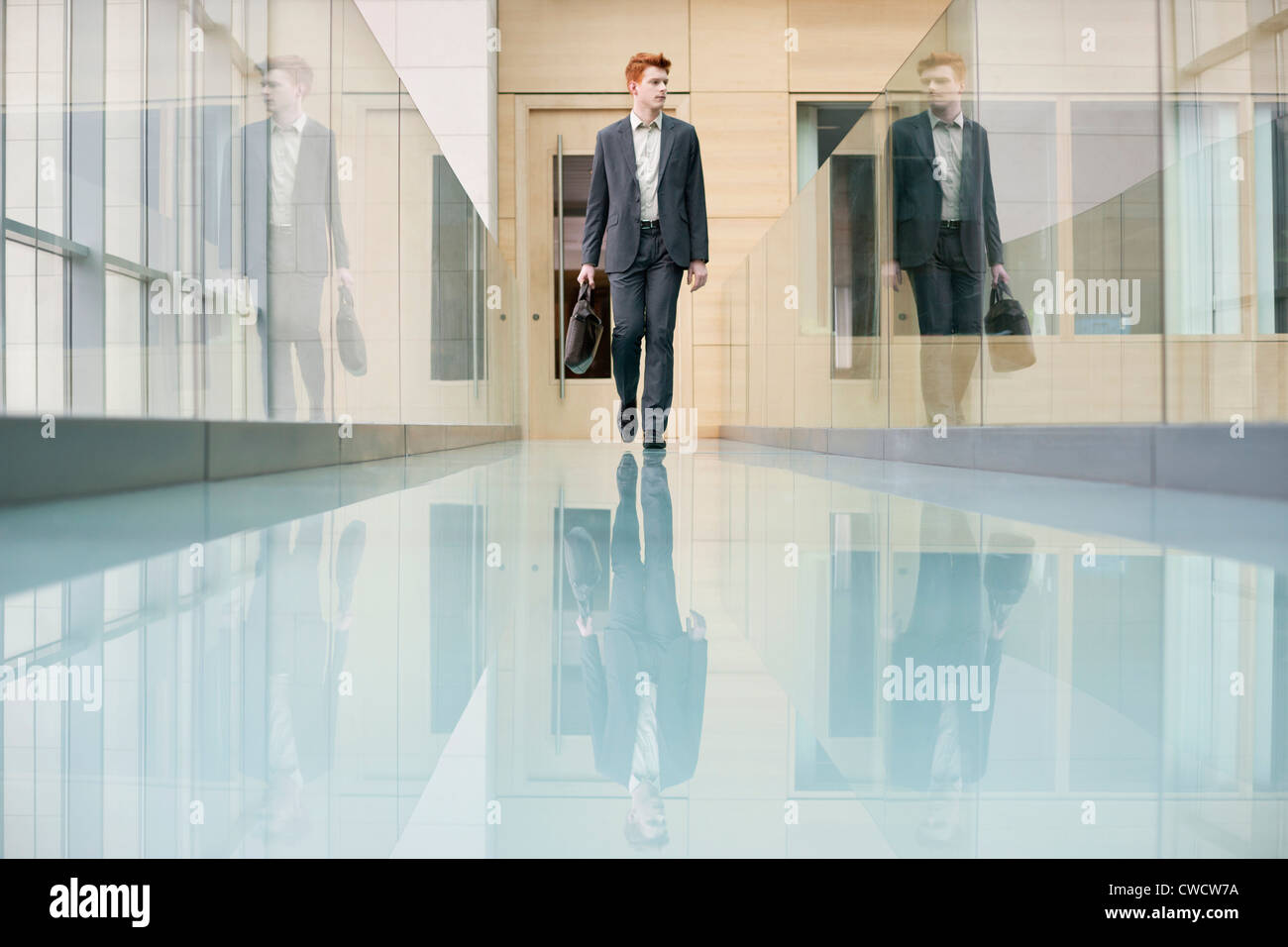 Businessman walking in an office corridor Stock Photo - Alamy