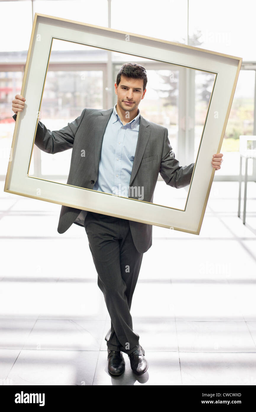 Businessman holding a frame in an office lobby Stock Photo - Alamy