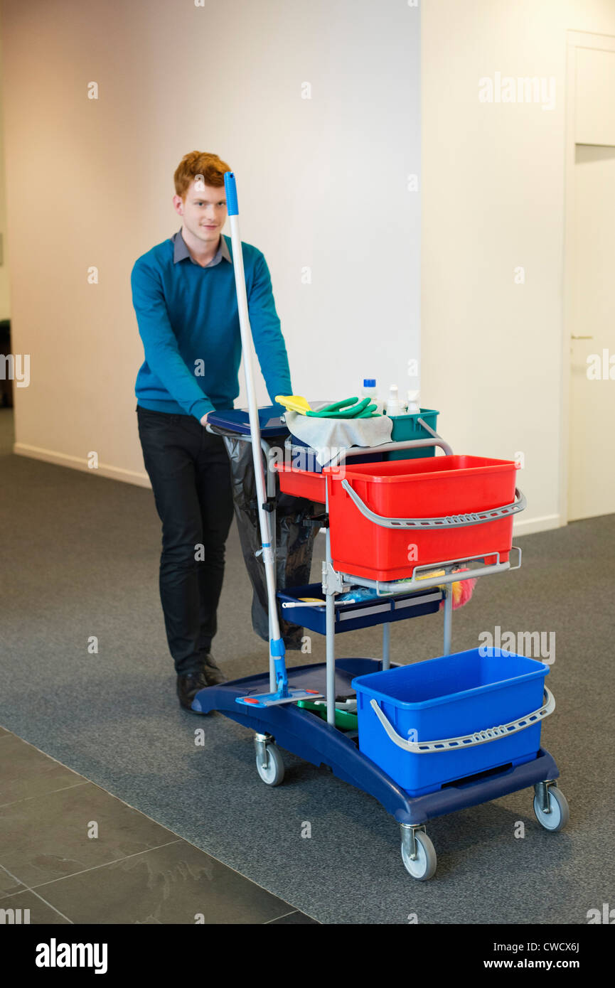 Male cleaner pushing trolley with cleaning equipment Stock Photo - Alamy