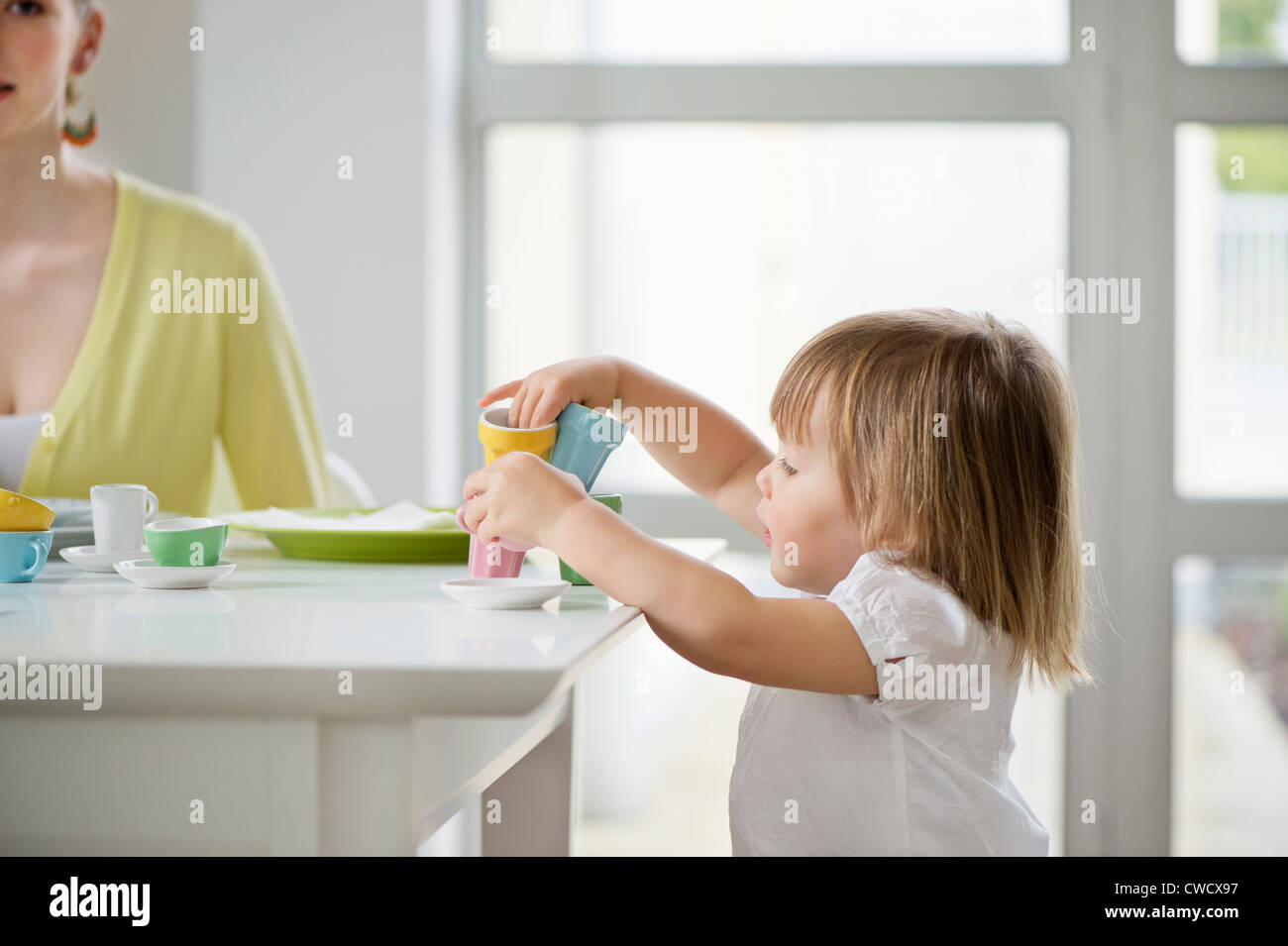 Cute little girl picking up toy tea set from a dining table Stock Photo ...