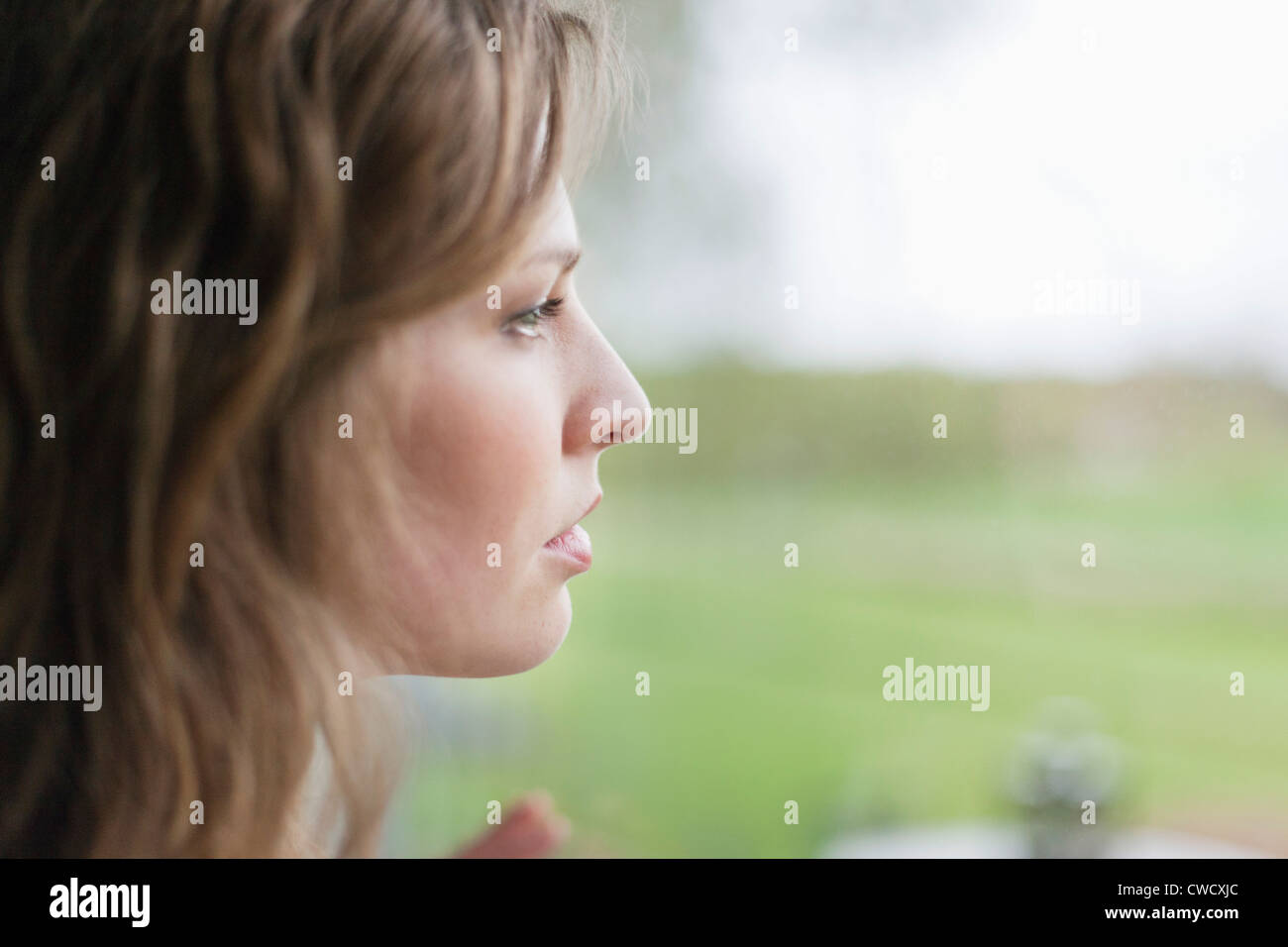 Woman looking through the glass of window Stock Photo - Alamy