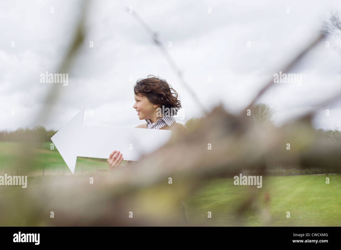 Boy holding an arrow sign in a field Stock Photo - Alamy