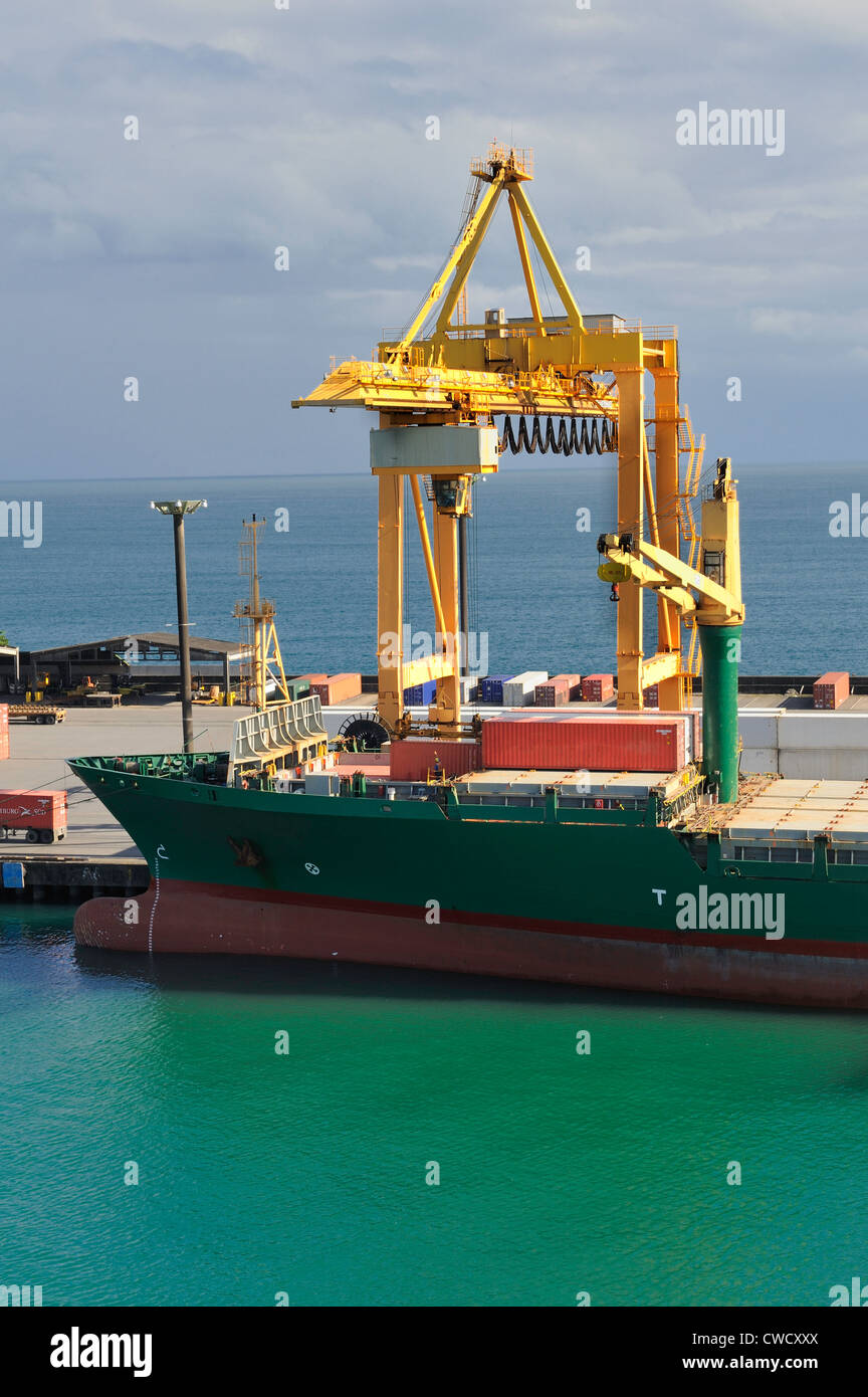 Cargo ship being loaded with containers of merchandise at the docks in ...