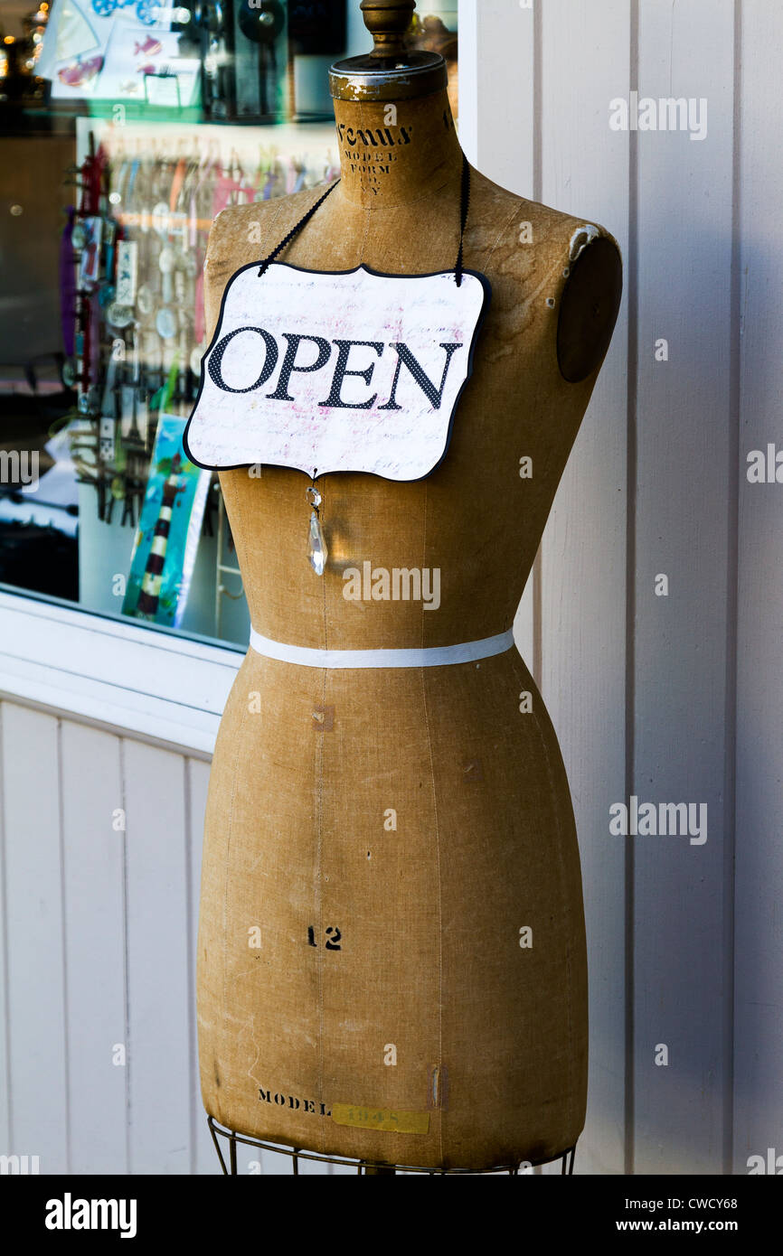 A dressmaker's dummy serves as a sign board for an "open" sign outside ...