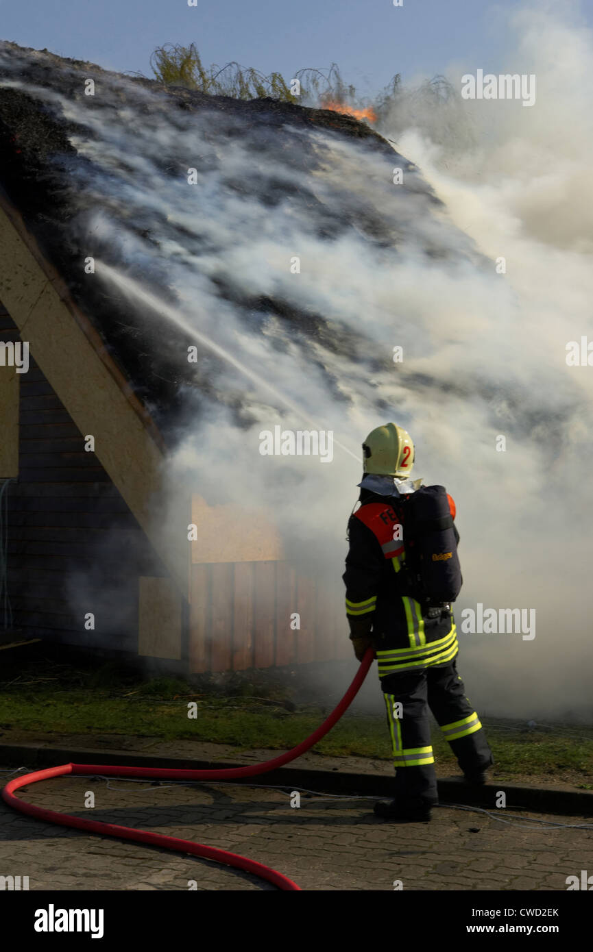 Firefighters, fire and thatched Stock Photo - Alamy