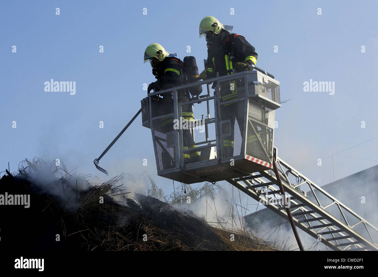Firefighters, fire and thatched Stock Photo - Alamy