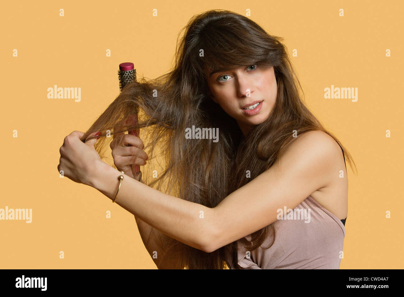 Portrait of a young woman brushing hair over colored background Stock ...