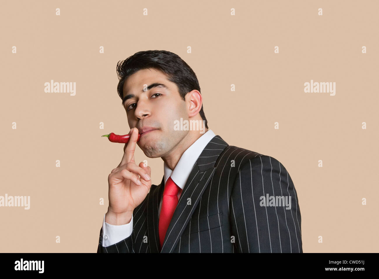 Portrait of a young businessman with red chili pepper imitating as ...